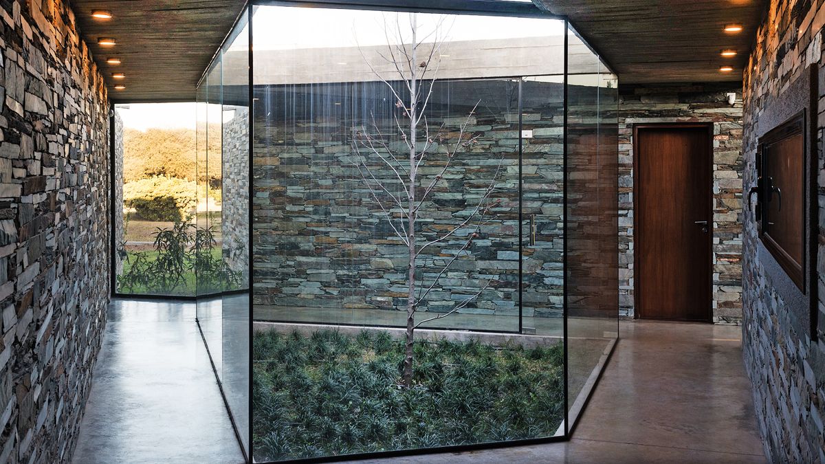 Un patio verde triangular es epicentro organizativo de una casa