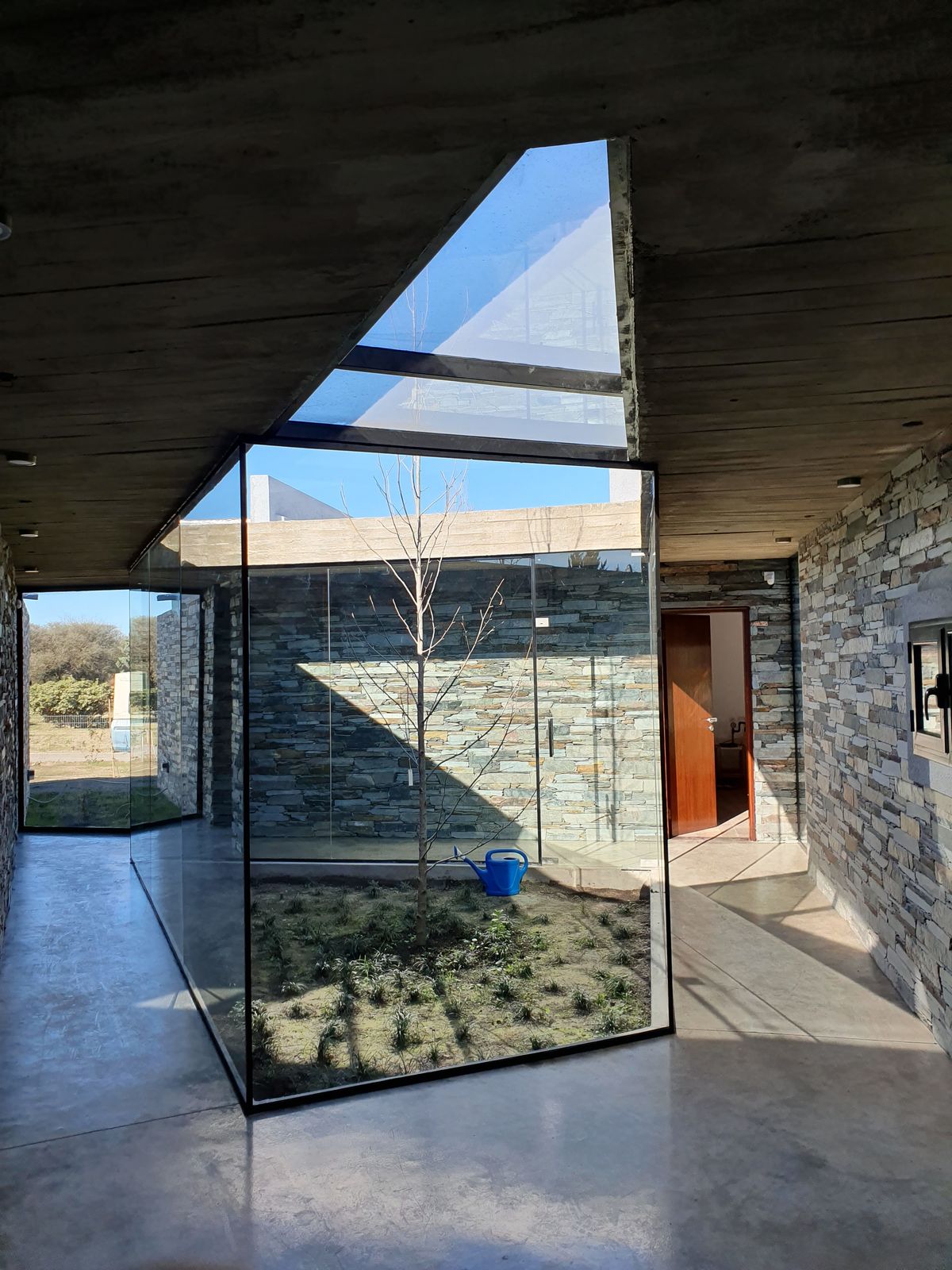 Un patio verde triangular es epicentro organizativo de una casa